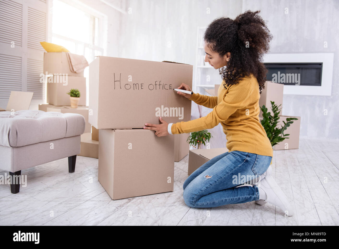 Curly-haired girl leaving note on box with home office things Stock ...