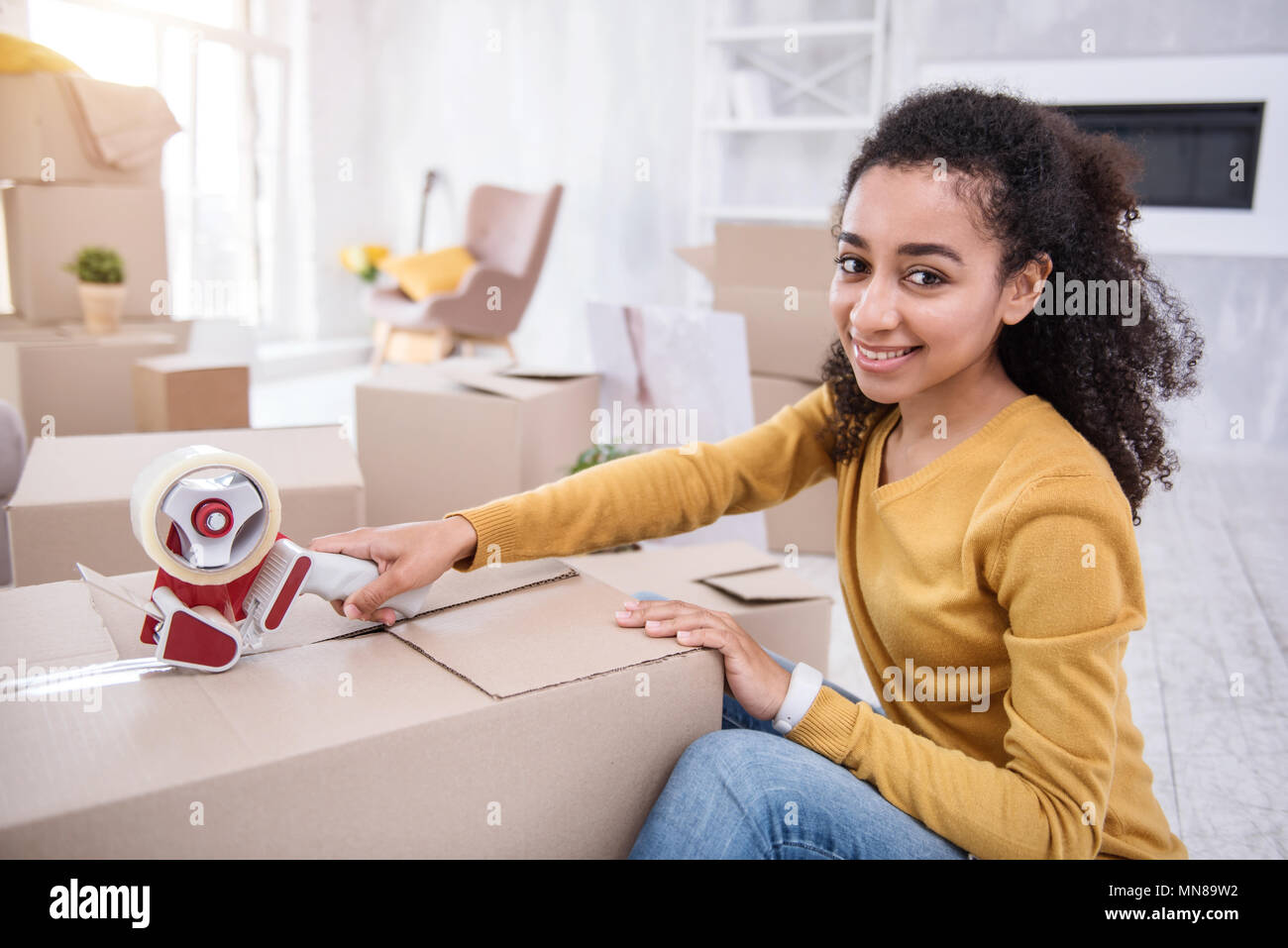 Cheerful girl posing while sealing box with adhesive tape Stock Photo ...