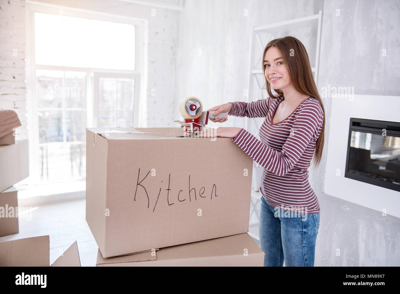 Joyful young woman closing box with kitchen utensils Stock Photo - Alamy
