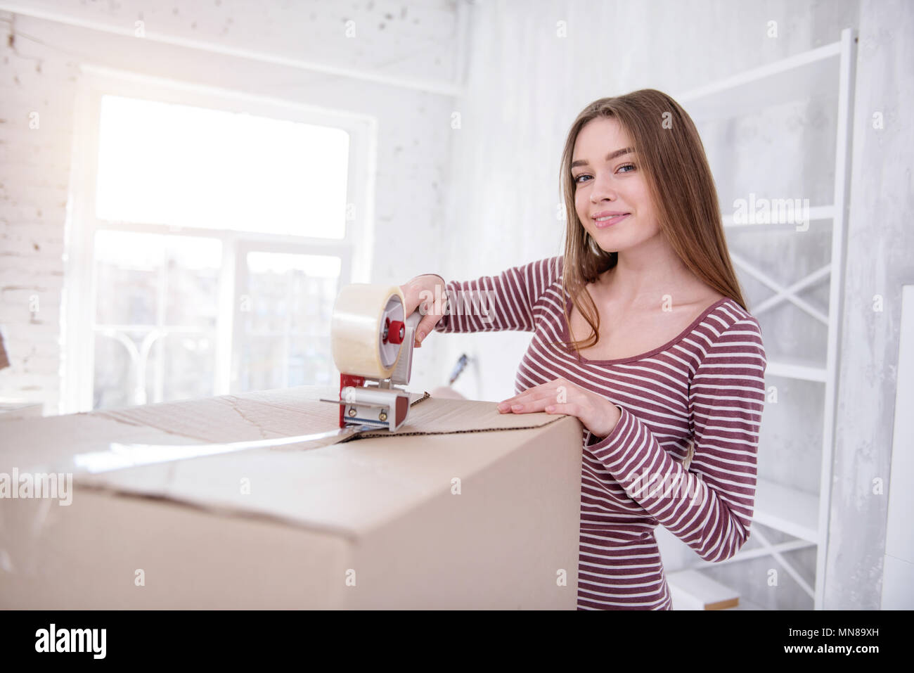 Beautiful dark-haired girl packing and closing box Stock Photo - Alamy