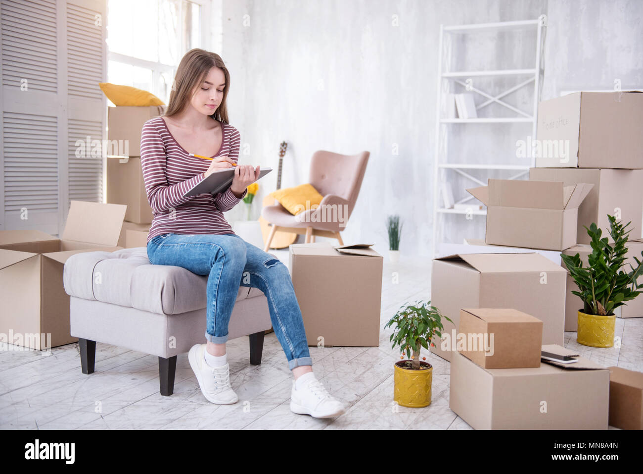 Charming young woman checking list of boxes Stock Photo - Alamy