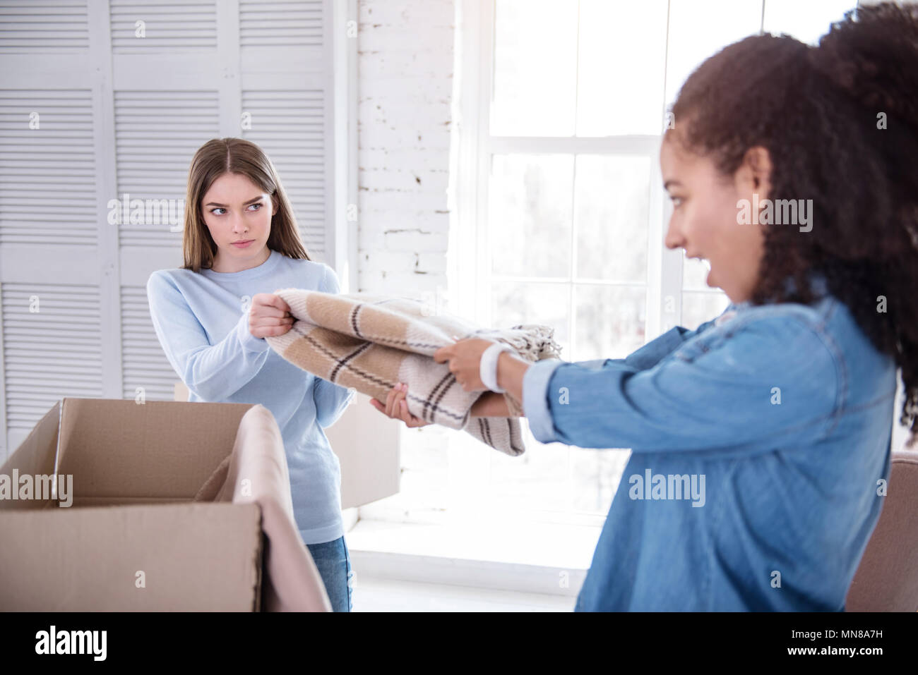 Young female students being unable to share blanket Stock Photo - Alamy