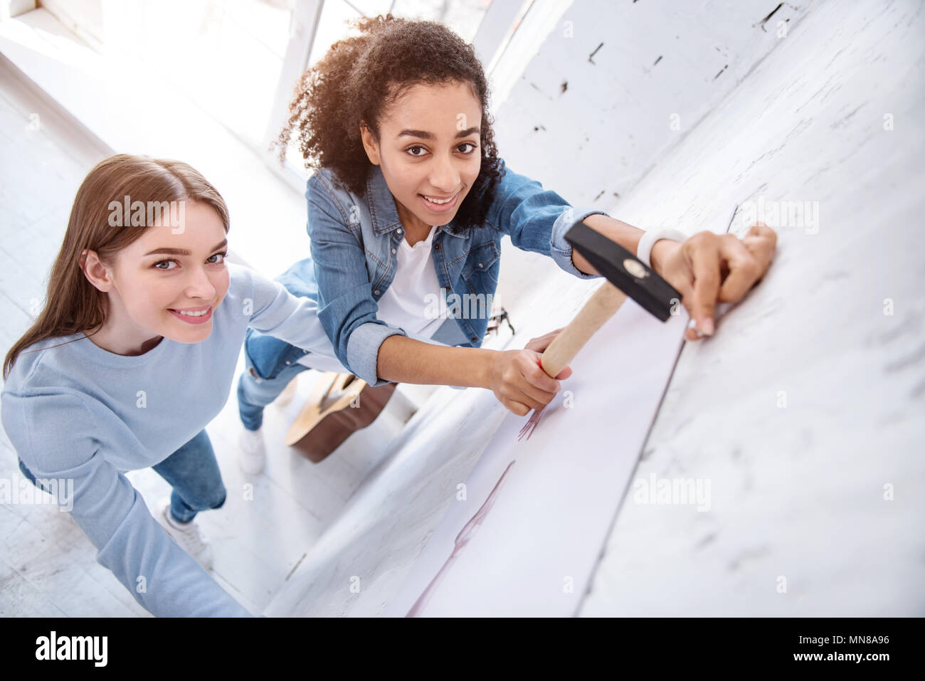 Top view of cheerful girls hanging a picture Stock Photo - Alamy