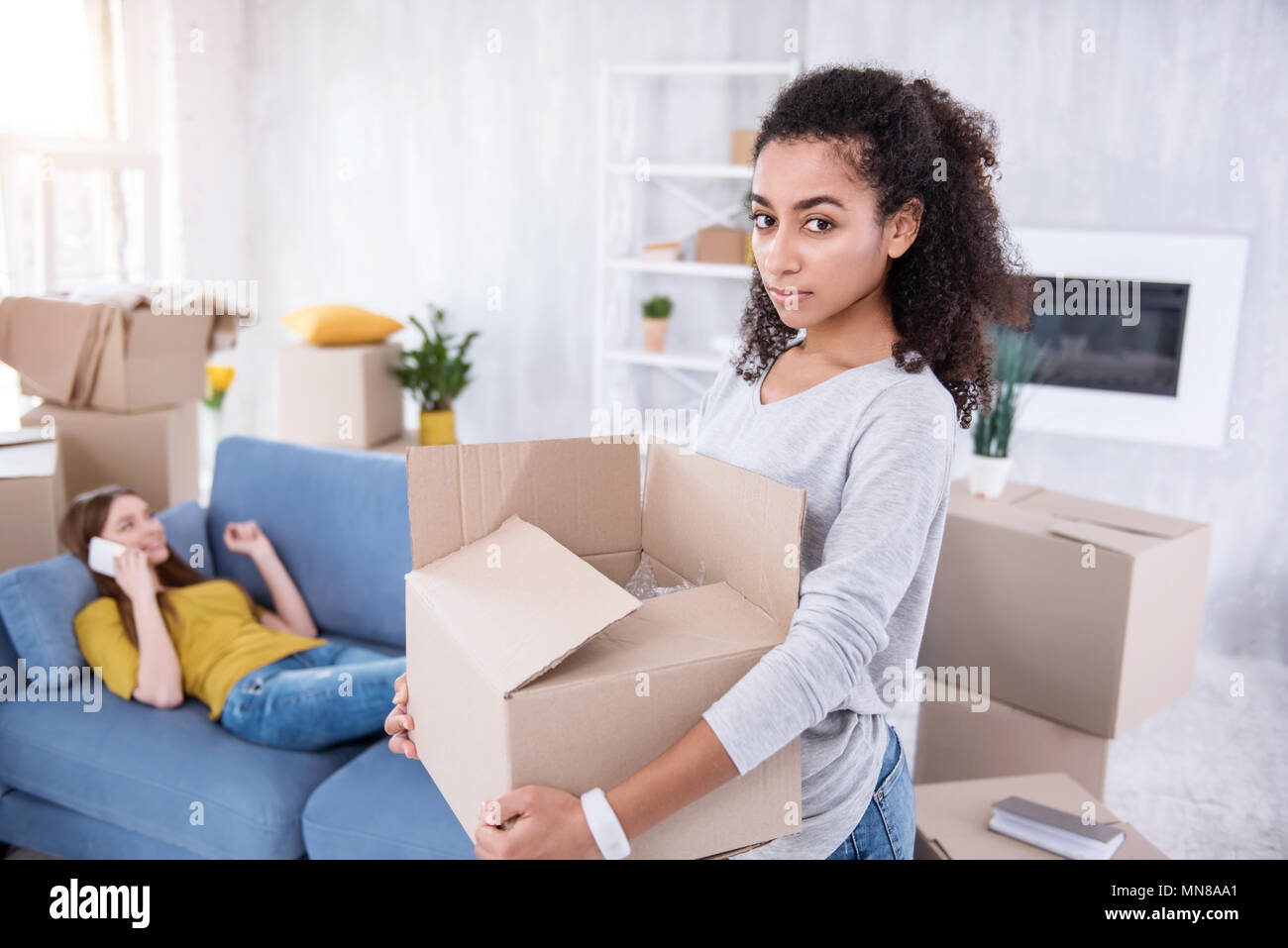 Upset young girl unpacking while her roommate talking on phone Stock ...
