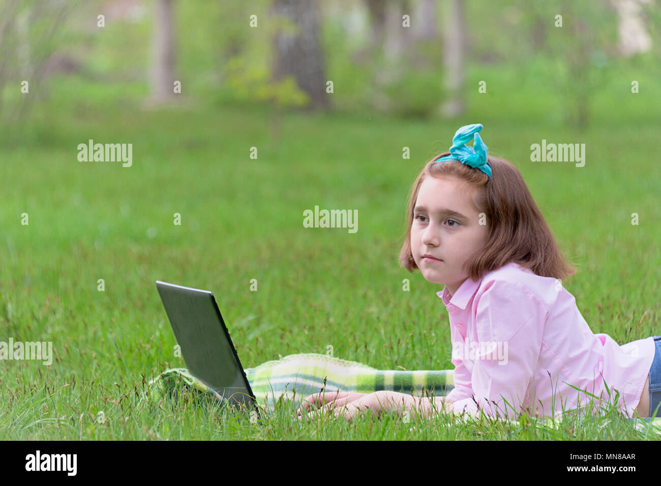 girl child with laptop outdoors resting on green grass Stock Photo - Alamy