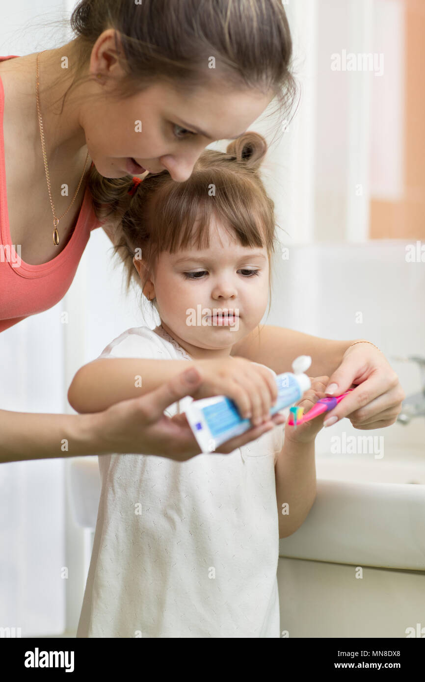 Mother puts toothpaste on a child brush, brushing teeth Stock Photo - Alamy