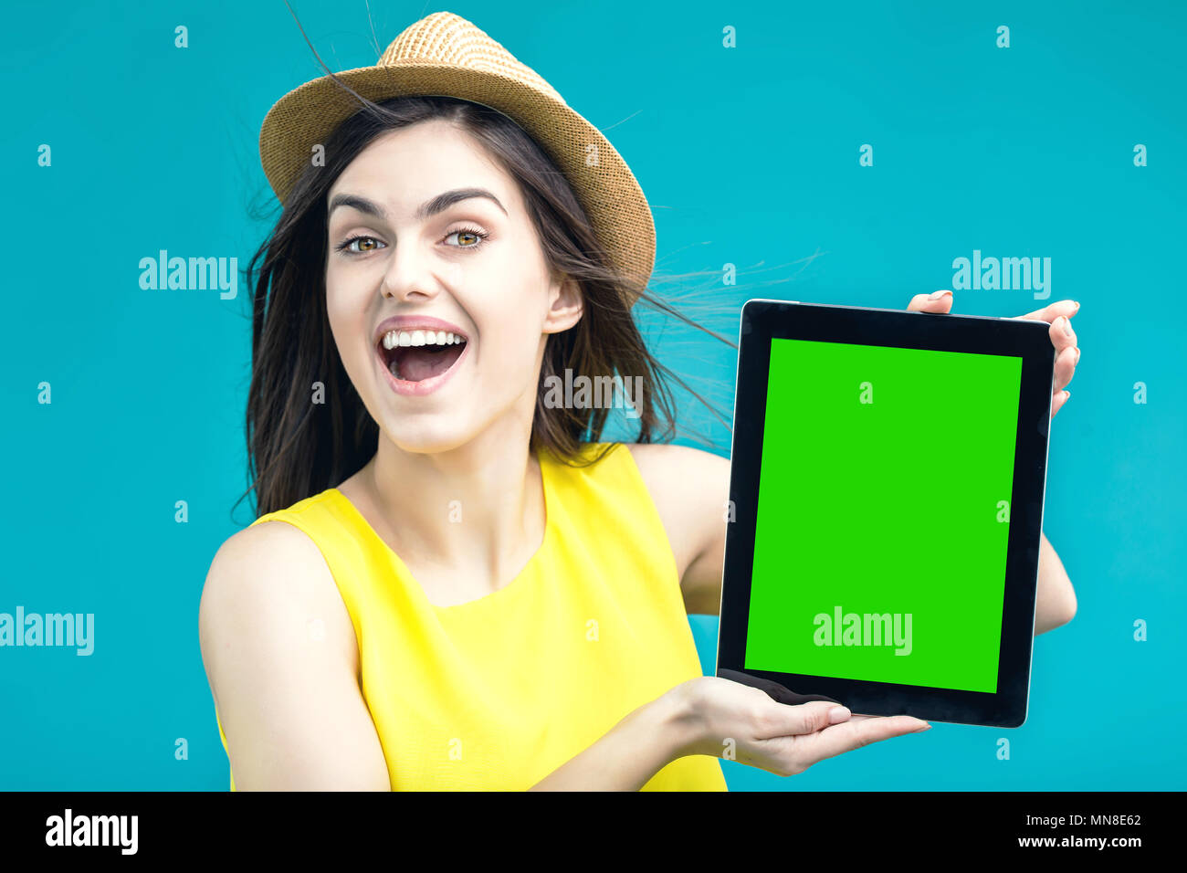 Pretty smiling brunette girl dressed in yellow shirt and hat holds ...