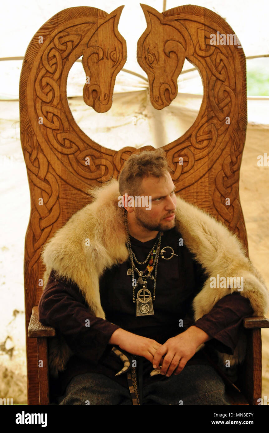 Viking sat in ornate wooden chair wearing animal skin Stock Photo - Alamy