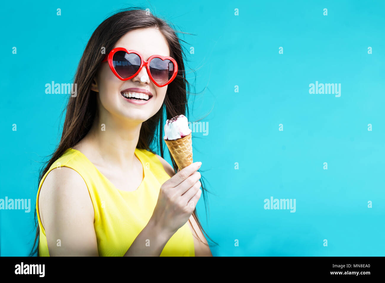 Pretty brunette woman dressed in yellow shirt and sunglasses eating ...