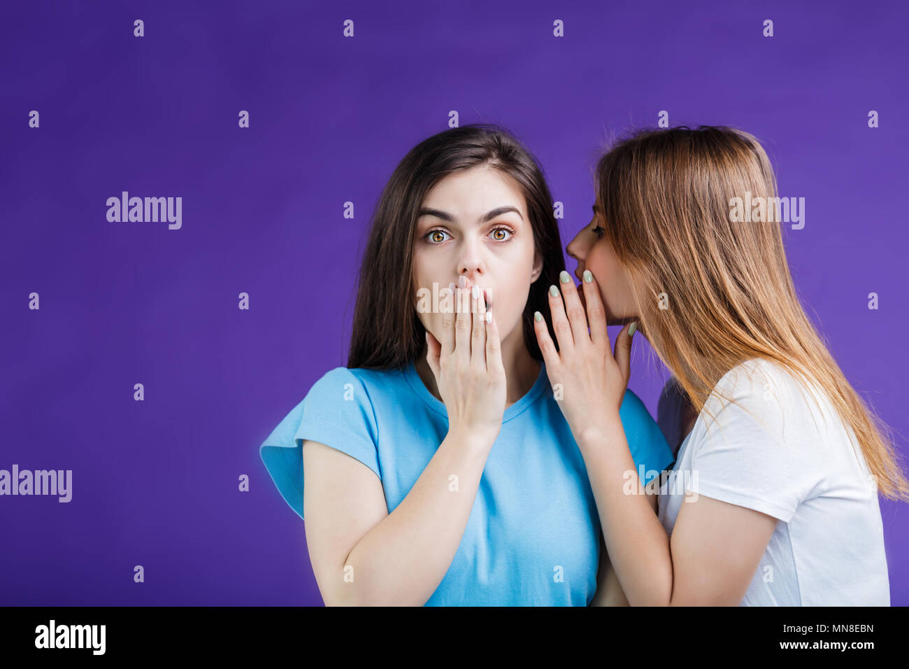Two pretty women gossipping with face reaction expression before blue ...