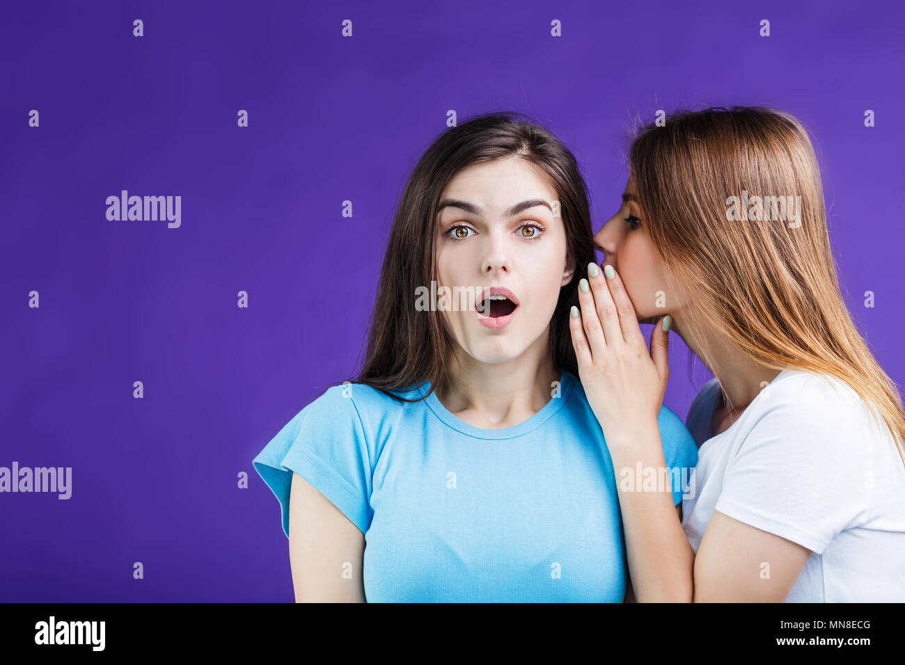 Two pretty women gossipping with face reaction expression before blue ...