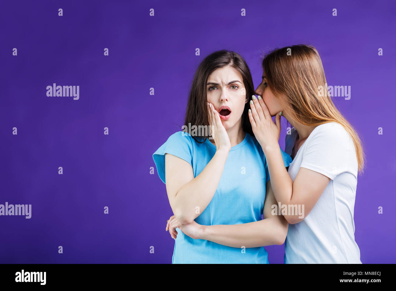 Two pretty women gossipping with face reaction expression before blue ...