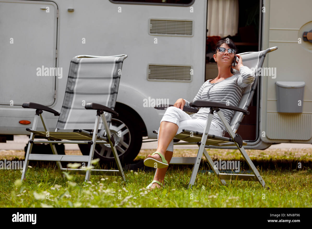 Woman talking on smart phone outdoors in a campsite for holidaymakers ...