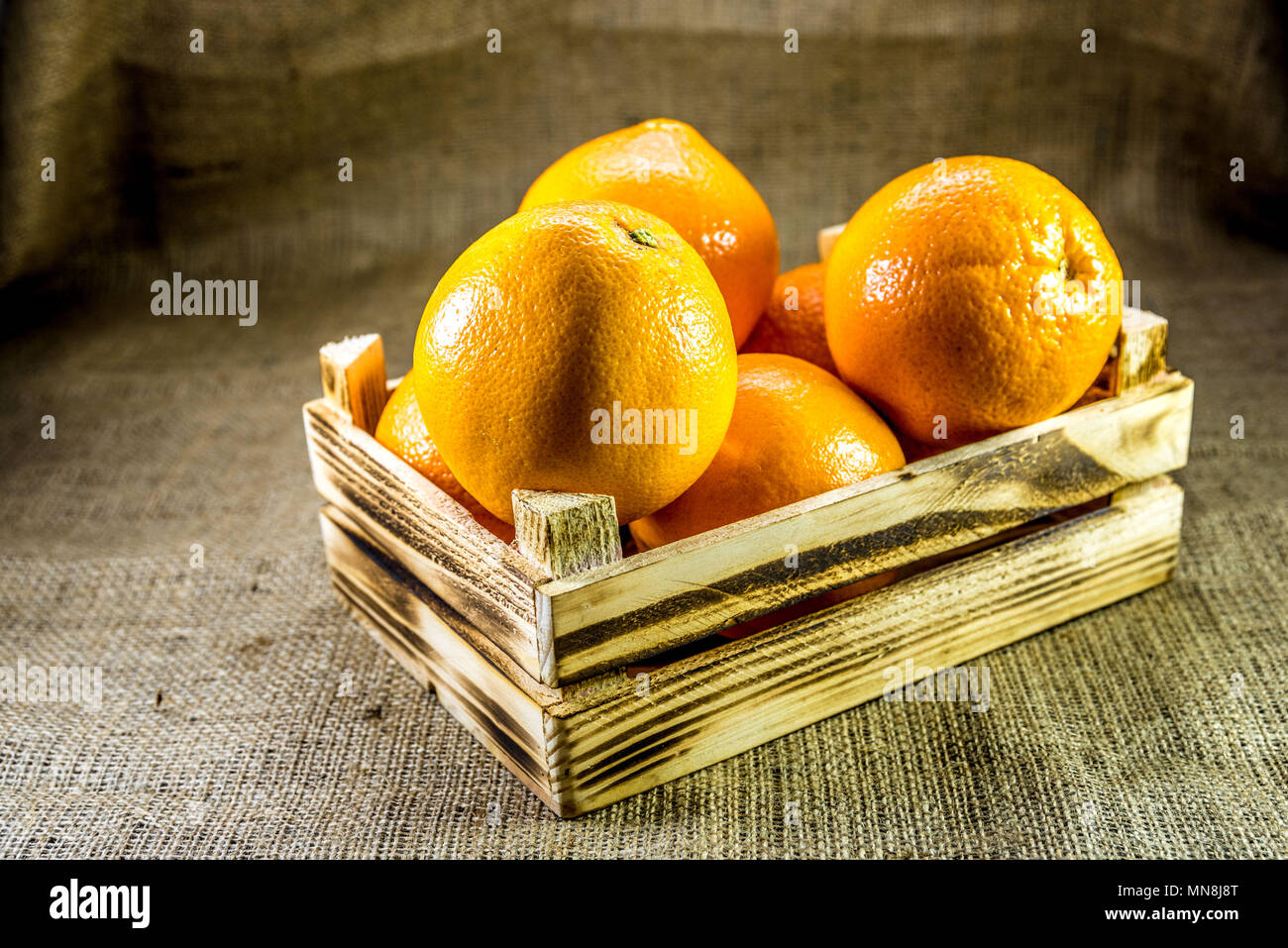 Fresh ripe orange fruits in old burnt wooden crate or box with ...