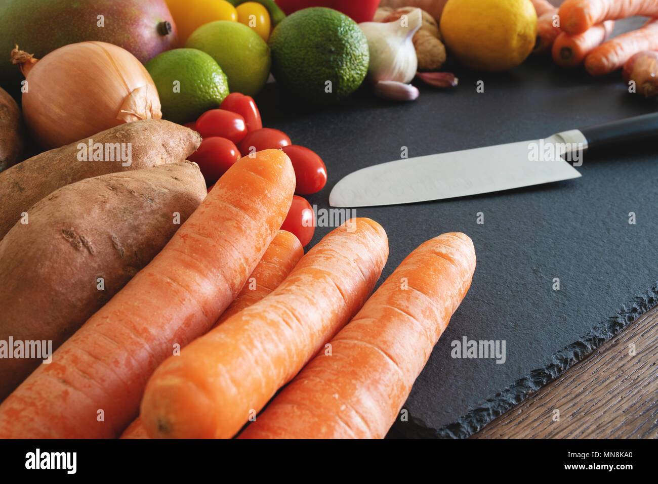 fresh organic fruits and vegetables on slate cutting board with kitchen ...