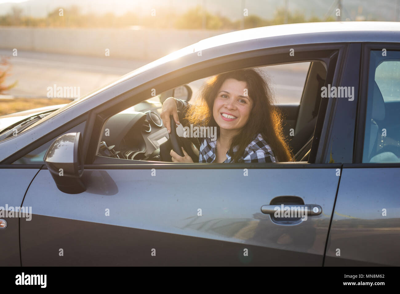 Smiling female driver looking out the car Stock Photo - Alamy