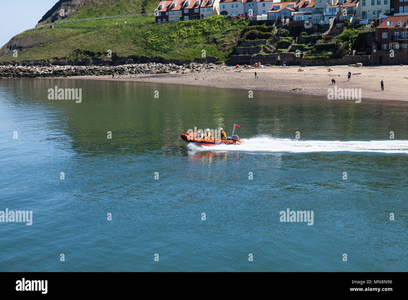 The RNLI lifeboat crew in their dinghy leaving the harbour at Whitby ...
