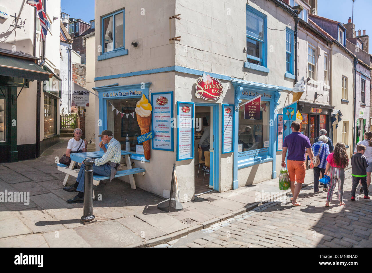 People sat outside an ice cream parlour in Whitby, North Yorkshire ...
