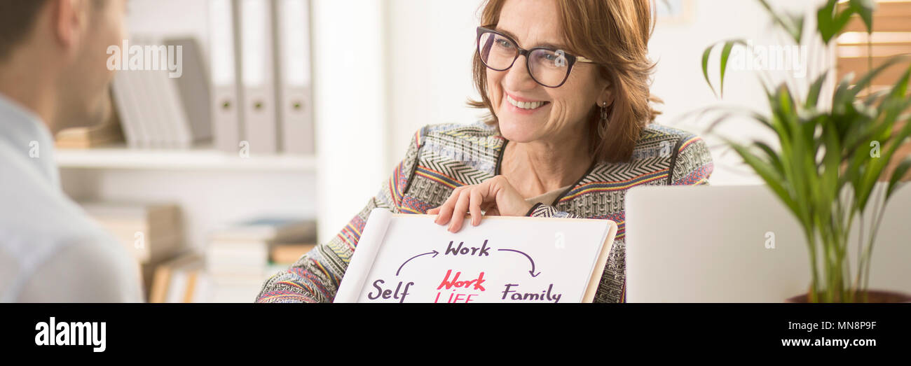 Smiling personal life coach showing a graph about work-life balance to ...