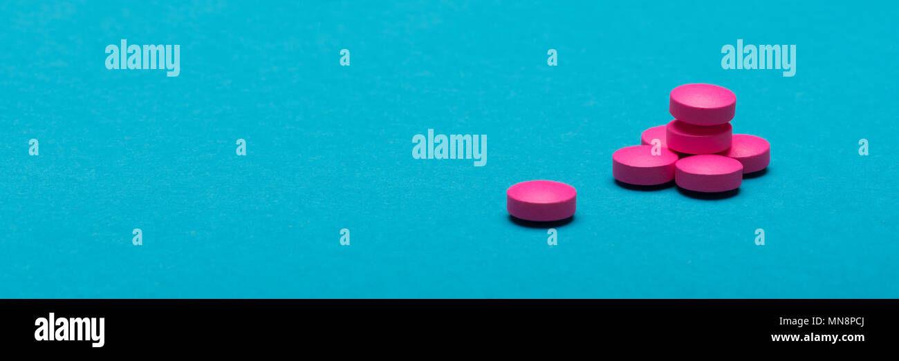 Bright pink pills on dark blue coloured background. Medication and ...