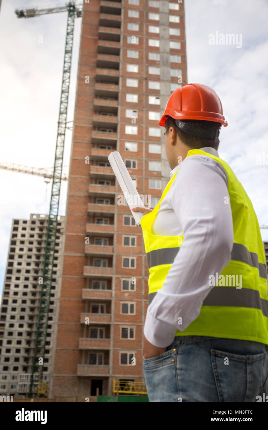 Rear view image of male architect pointing at buildings under ...