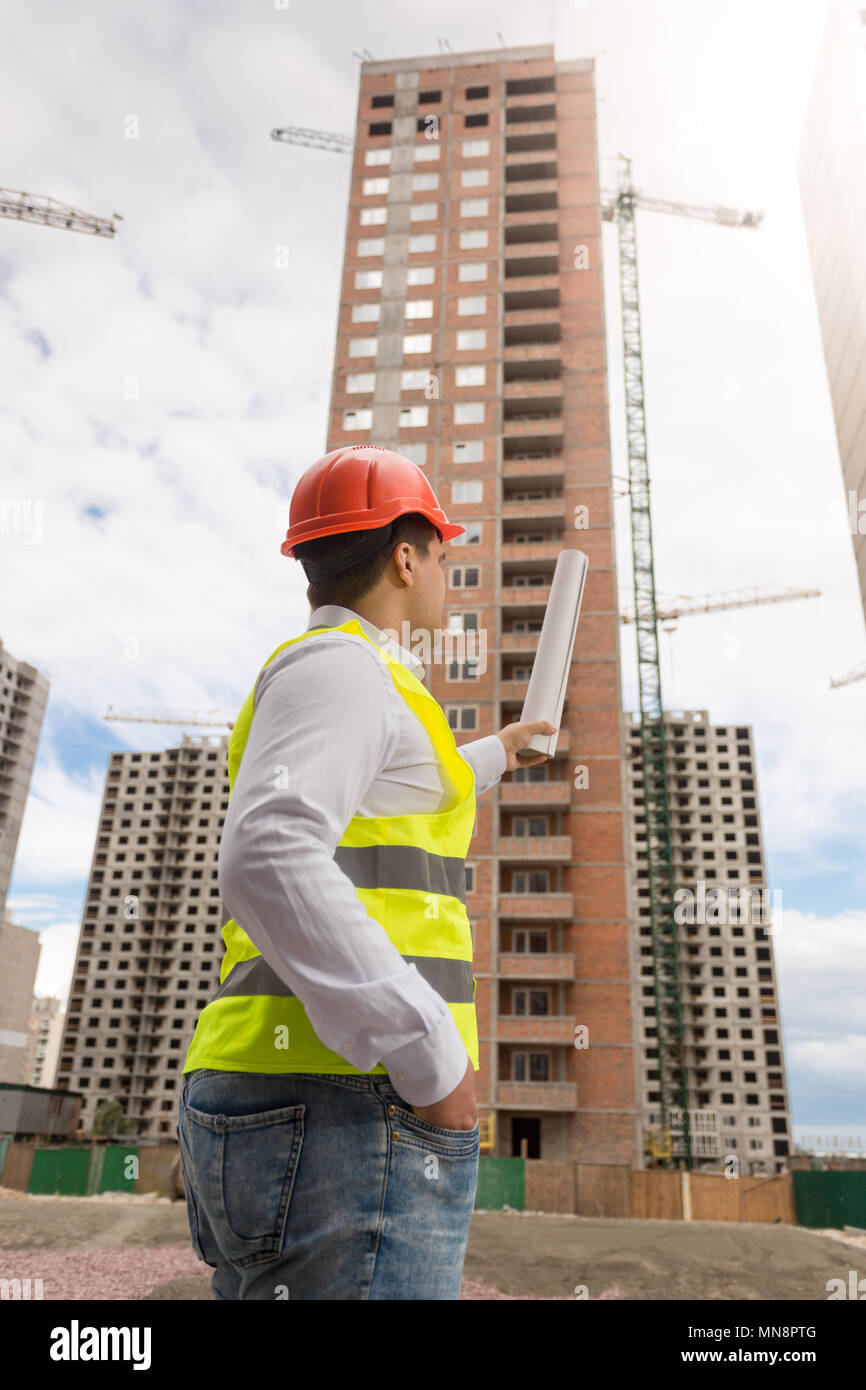 Male building engineer in hardhat pointing at construction site with ...