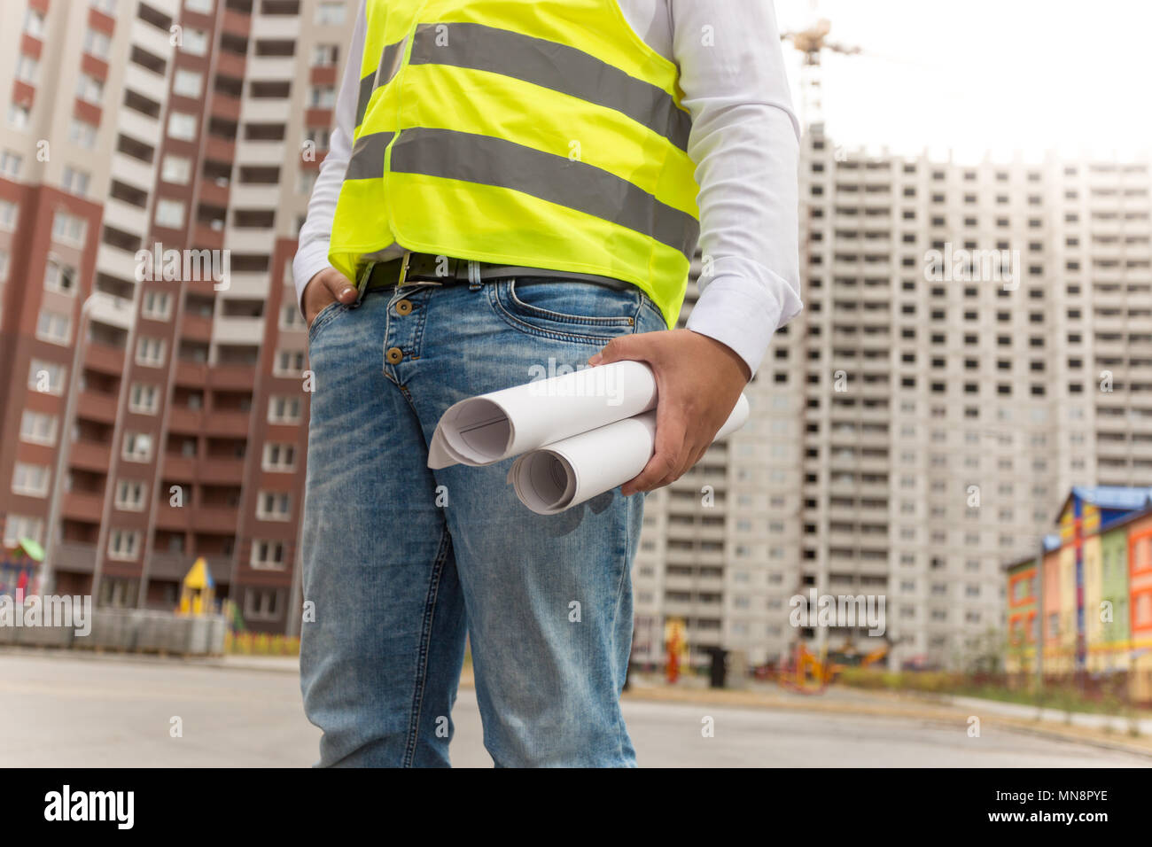Closeup image of male architect with blueprints standing next building ...
