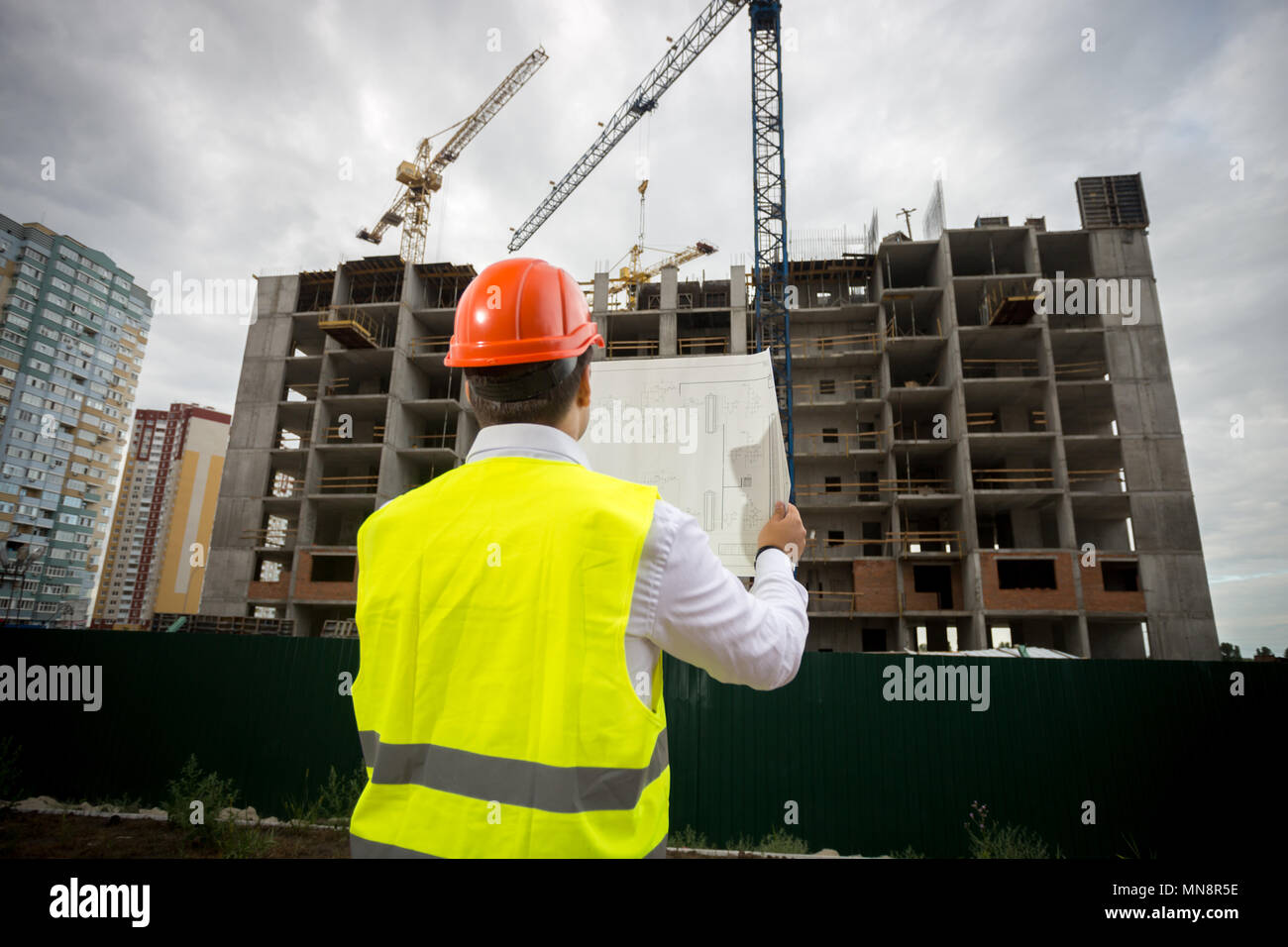 Rear view photo of male construction engineer with blueprints ...