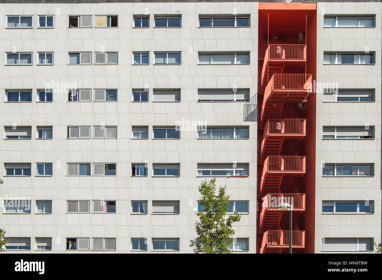 white facade with horizontal windows and orange staircase of a building ...