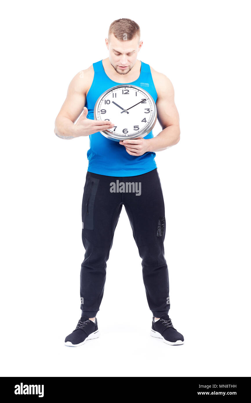 Full-length portrait of fit athlete holding wall clock on white ...