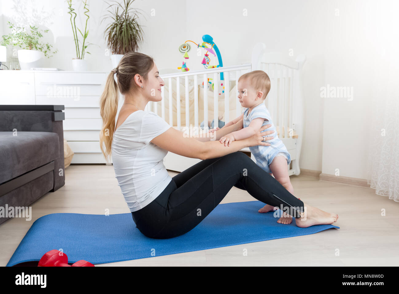 Cute baby boy exercising with young mother on fitness mat at home Stock ...