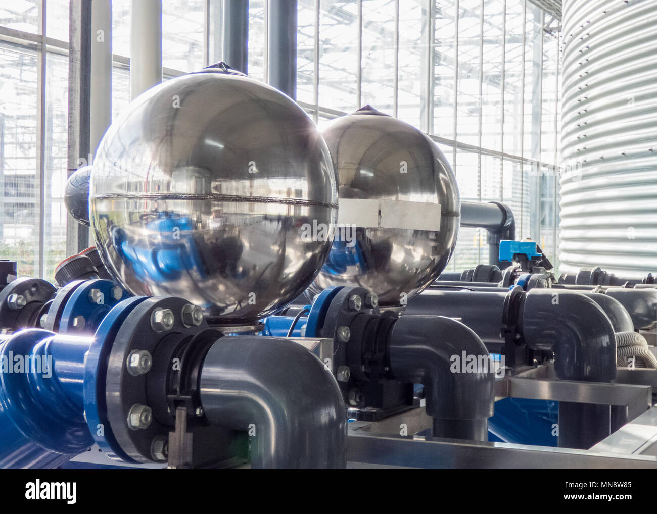 a range of plastic water pipes with large metal balls Stock Photo - Alamy