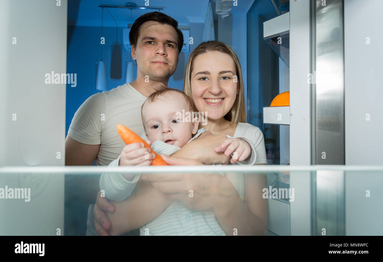 Portrait of hungry family with baby looking inside the refrigerator for ...