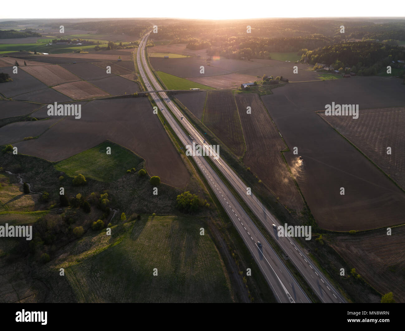 Aerial view of highway leading towards setting sun with cars on the ...