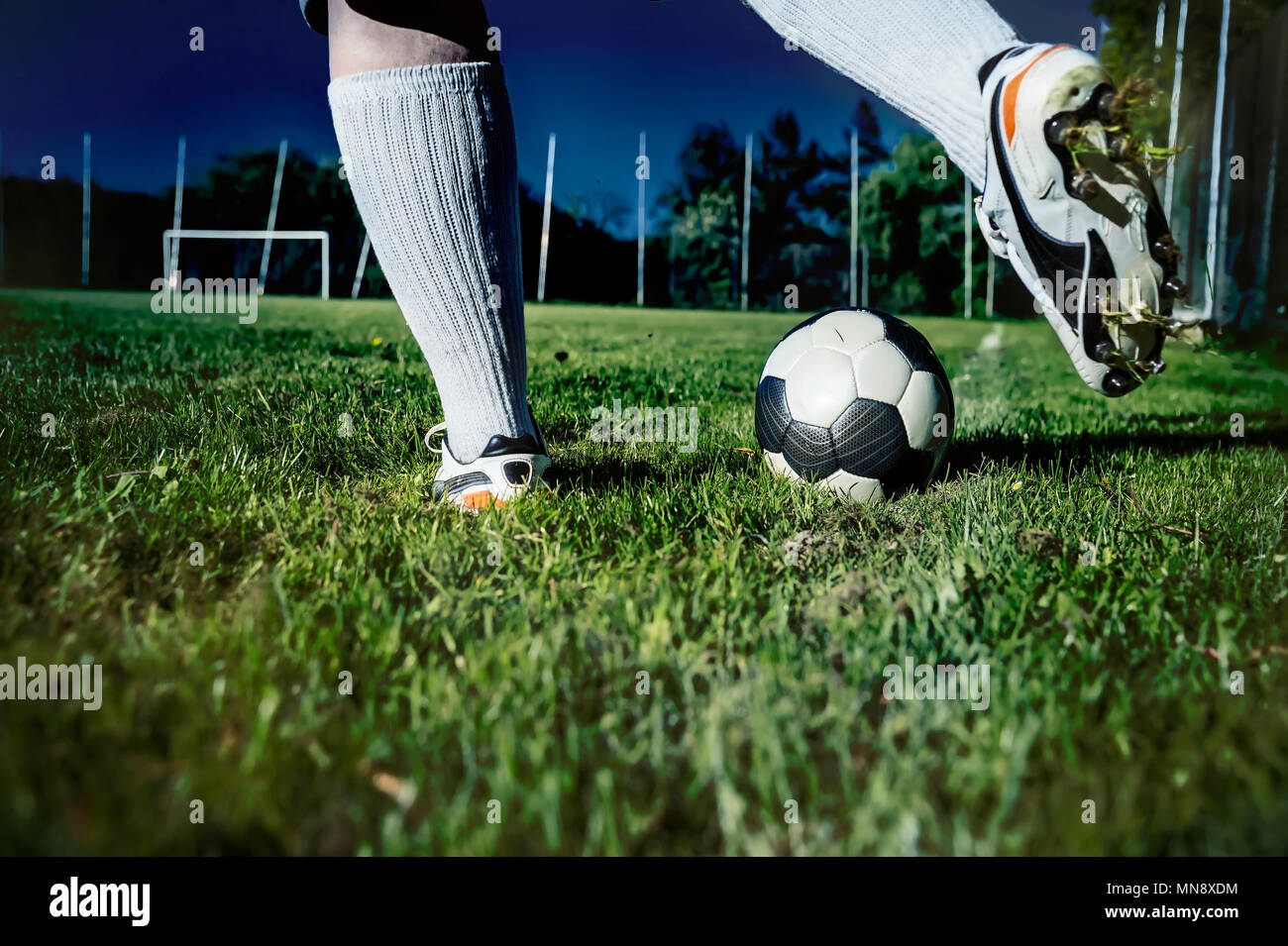 On a lighted soccer field a man plays all alone with a football. He ...