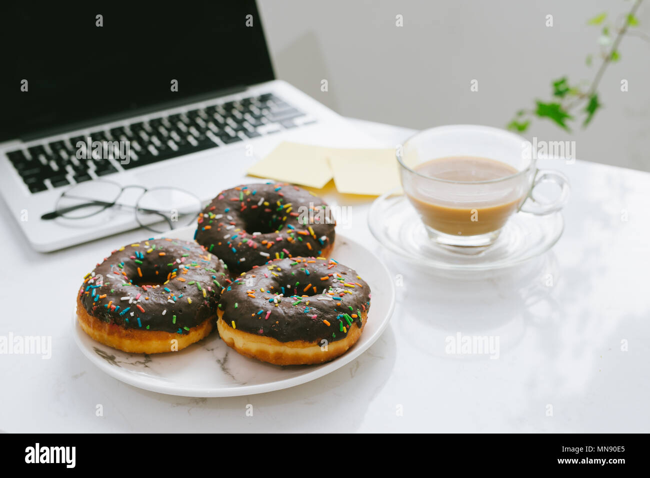Food in the office. Donuts on working desk Stock Photo - Alamy