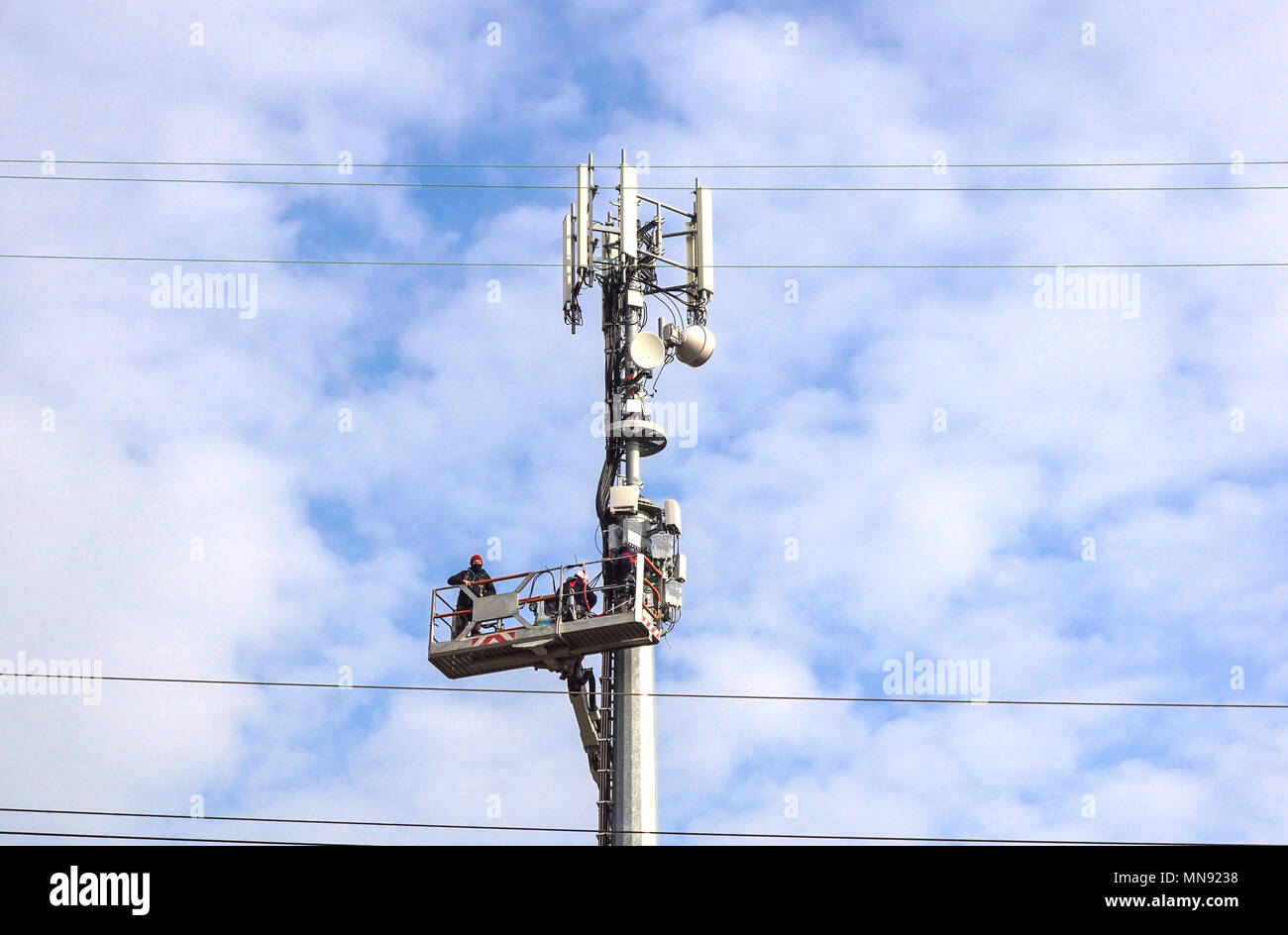 A worker performing maintenance to a GSM communication antenna Stock ...
