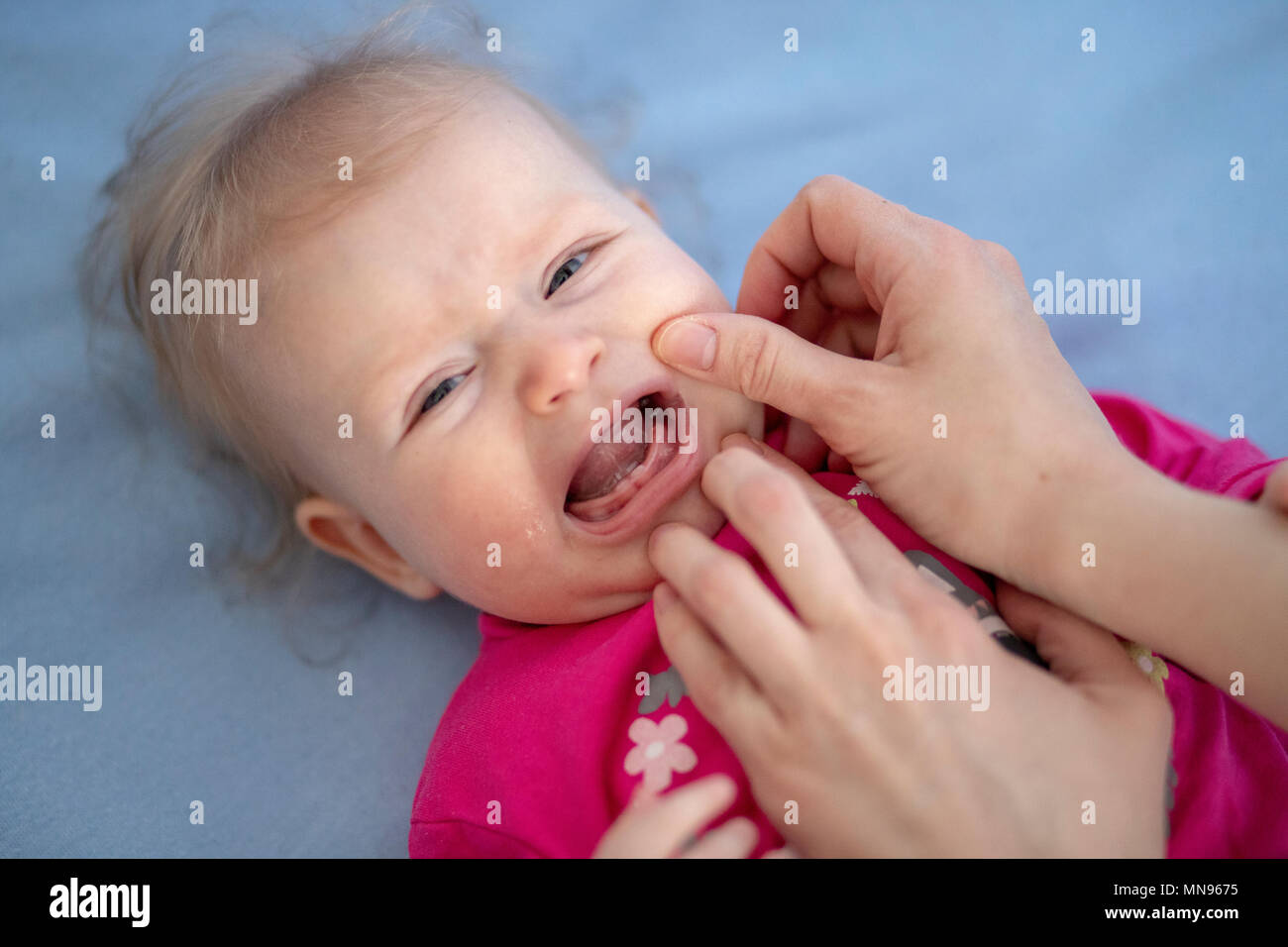 Crying baby in pain examined by mother Stock Photo - Alamy