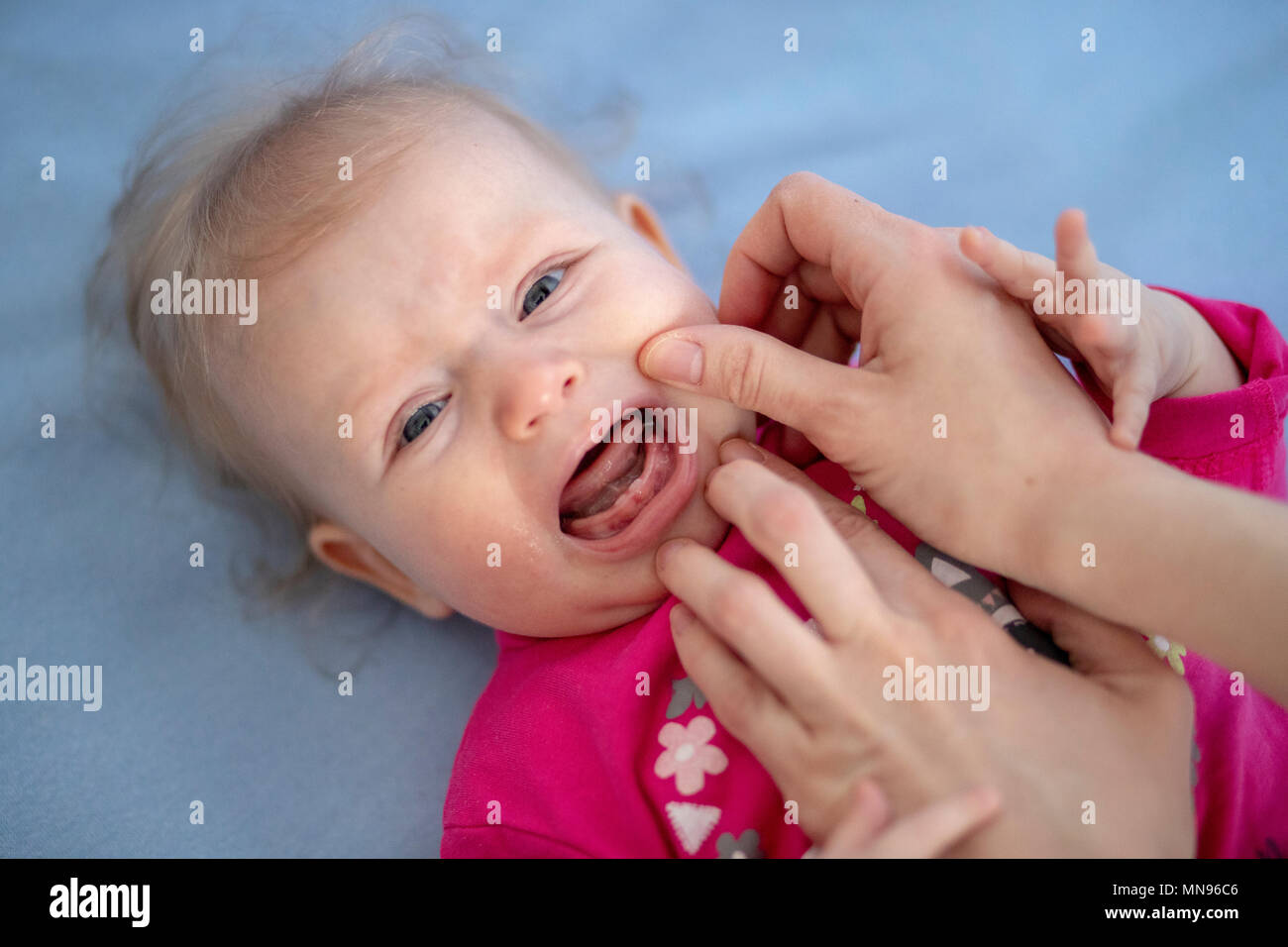 Crying baby in pain examined by mother Stock Photo - Alamy