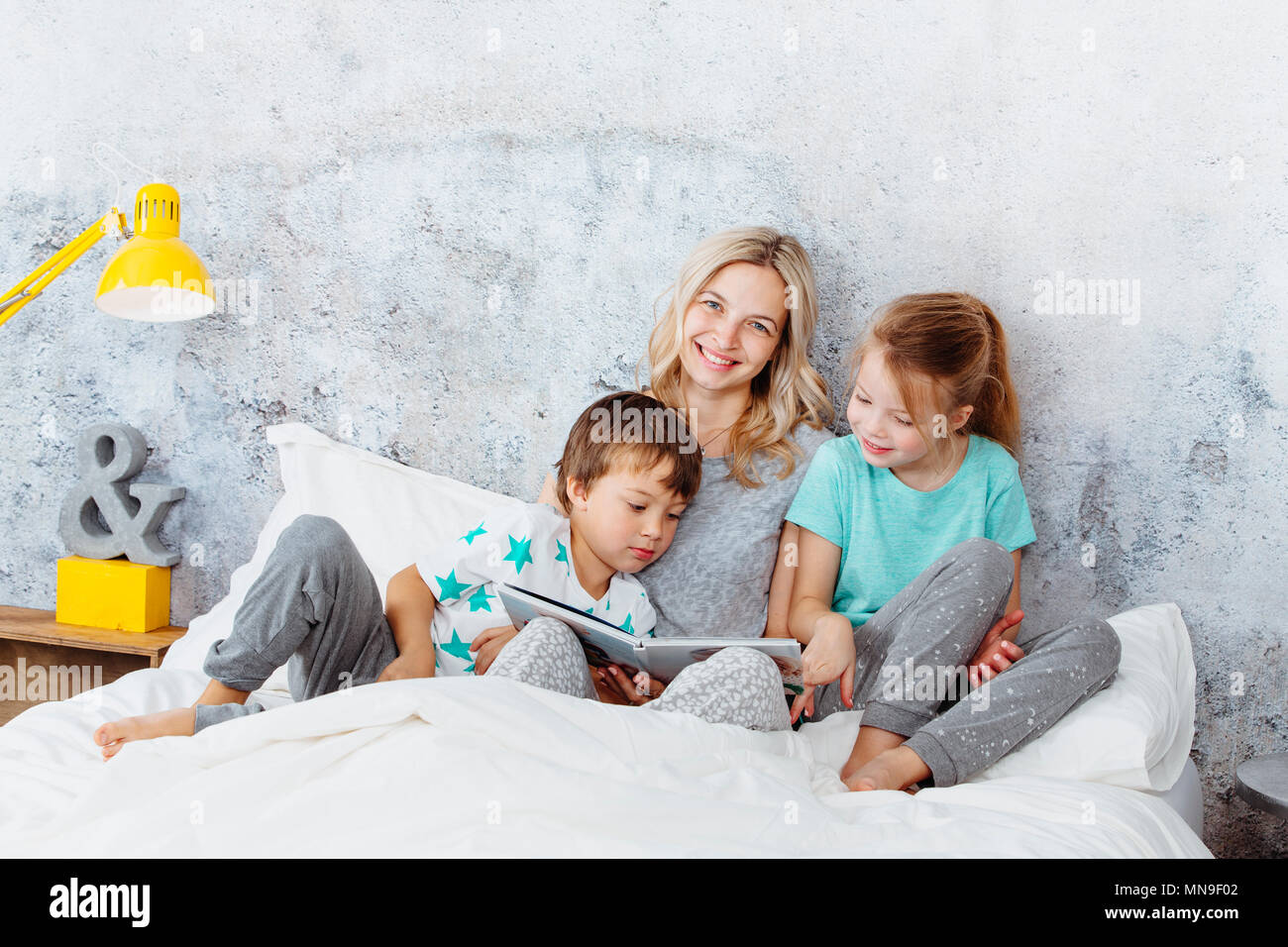 Beautiful mother is reading a story to her children Stock Photo - Alamy