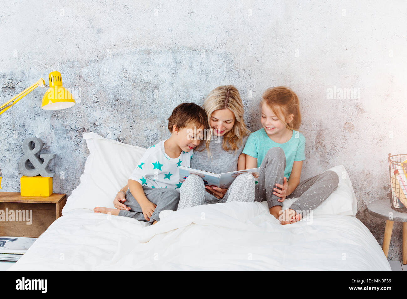 Beautiful mother is reading a story to her children Stock Photo - Alamy