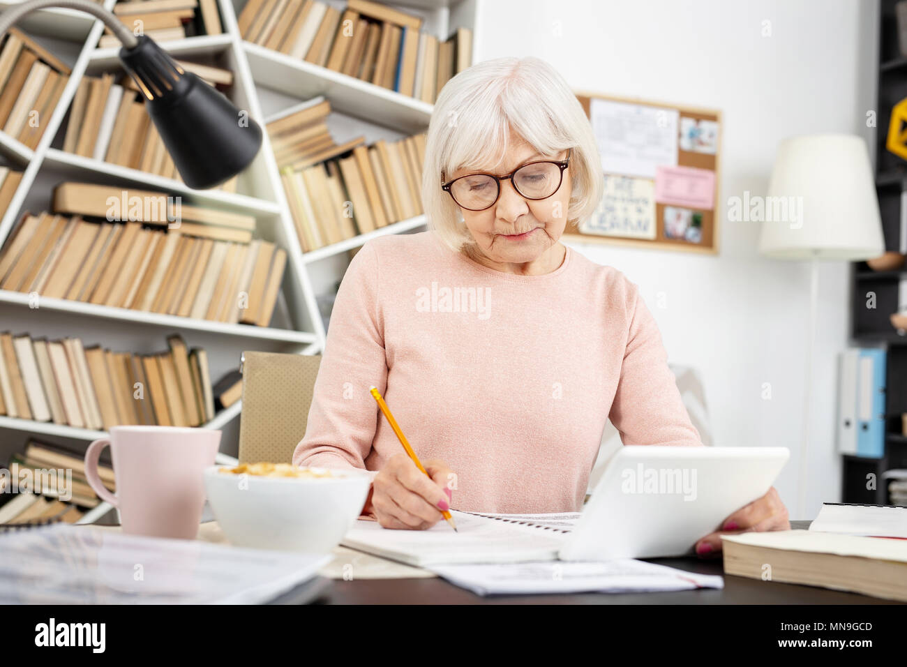 Earnest senior woman taking notes Stock Photo - Alamy