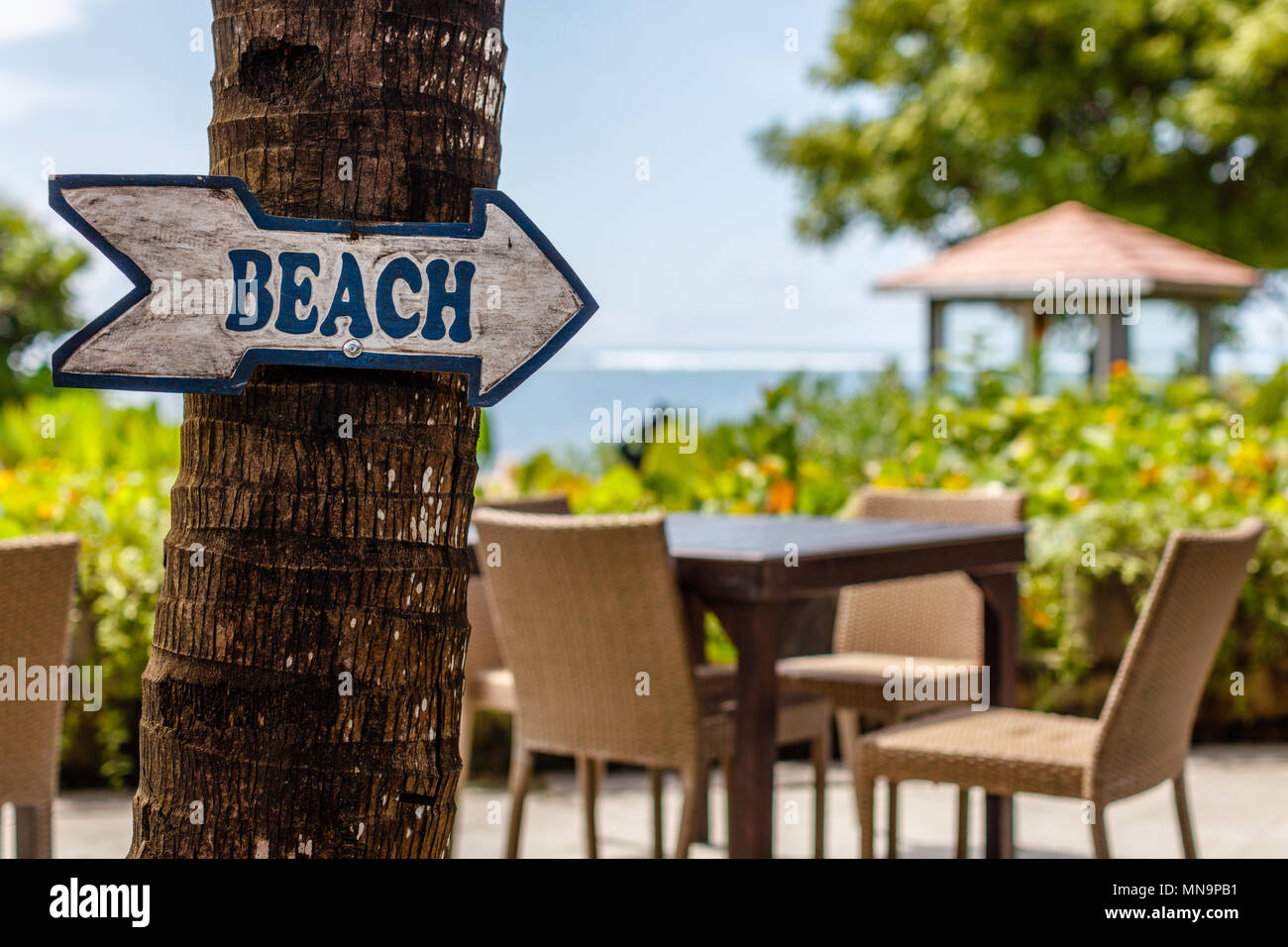 Outdoor cafe with an arrow sign BEACH, ocean on the background. Nusa ...