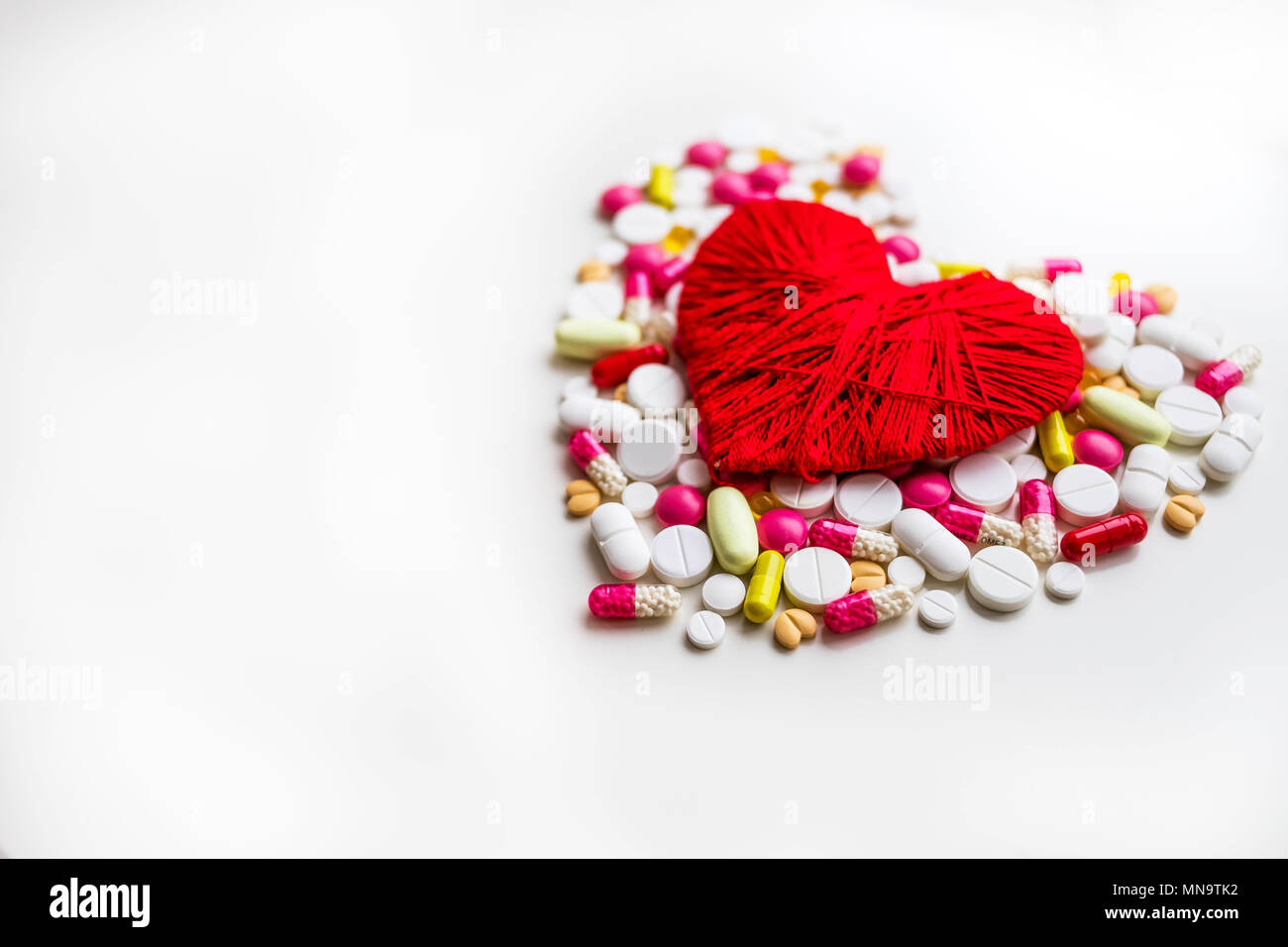 red heart with different pills over white background, healthy life ...