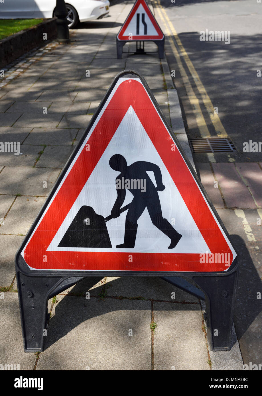 Triangular roadworks sign on pavement with road narrows on right sign ...
