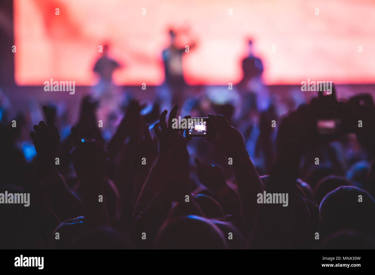 A crowded concert hall with scene stage lights, rock show performance ...