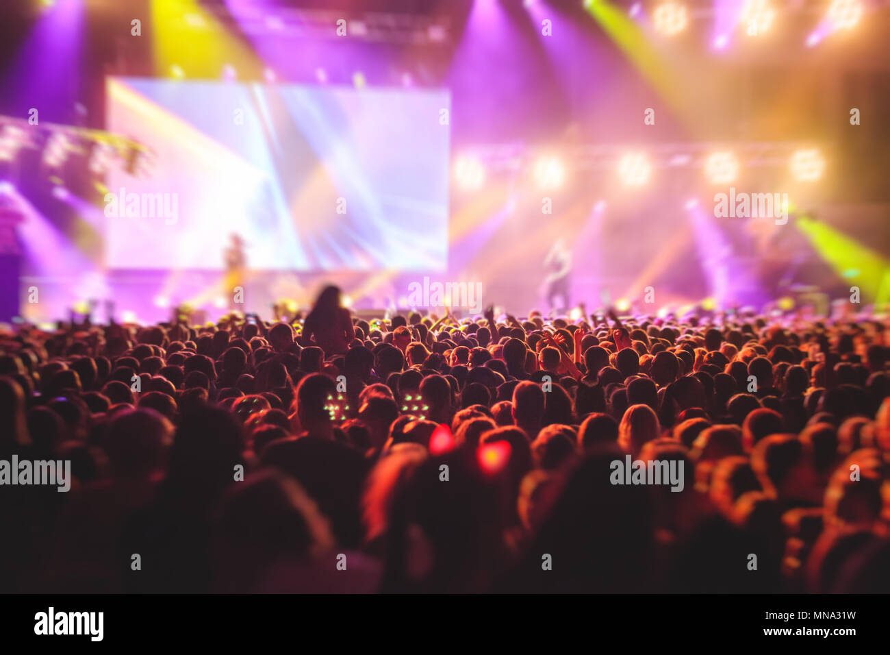 A crowded concert hall with scene stage lights, rock show performance ...