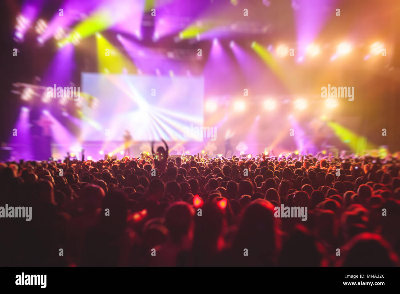 A crowded concert hall with scene stage lights, rock show performance ...