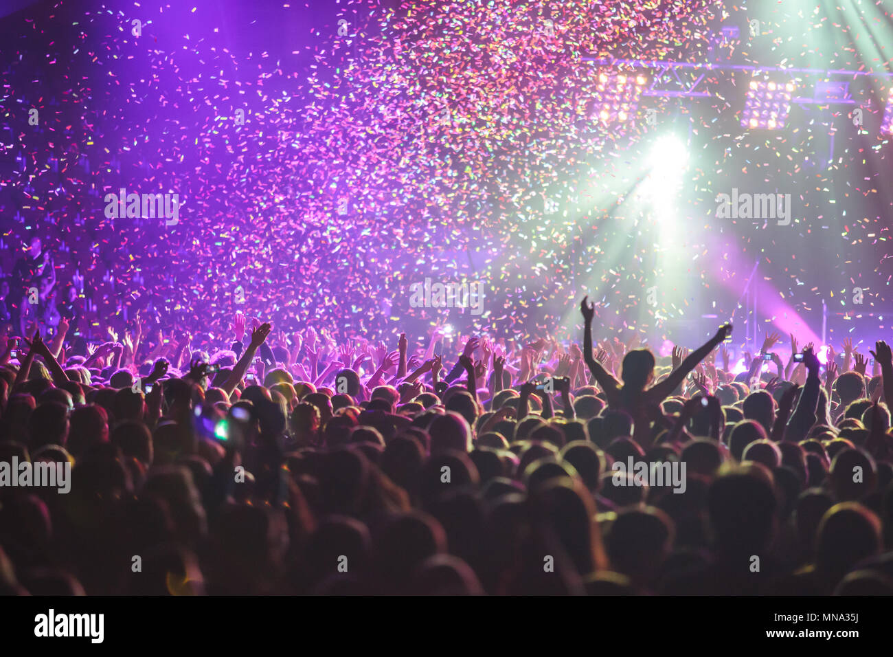 A crowded concert hall with scene stage lights, rock show performance ...