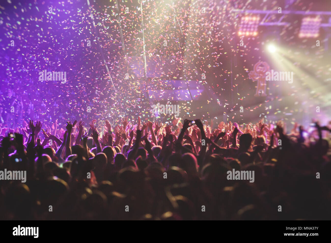 A crowded concert hall with scene stage lights, rock show performance ...